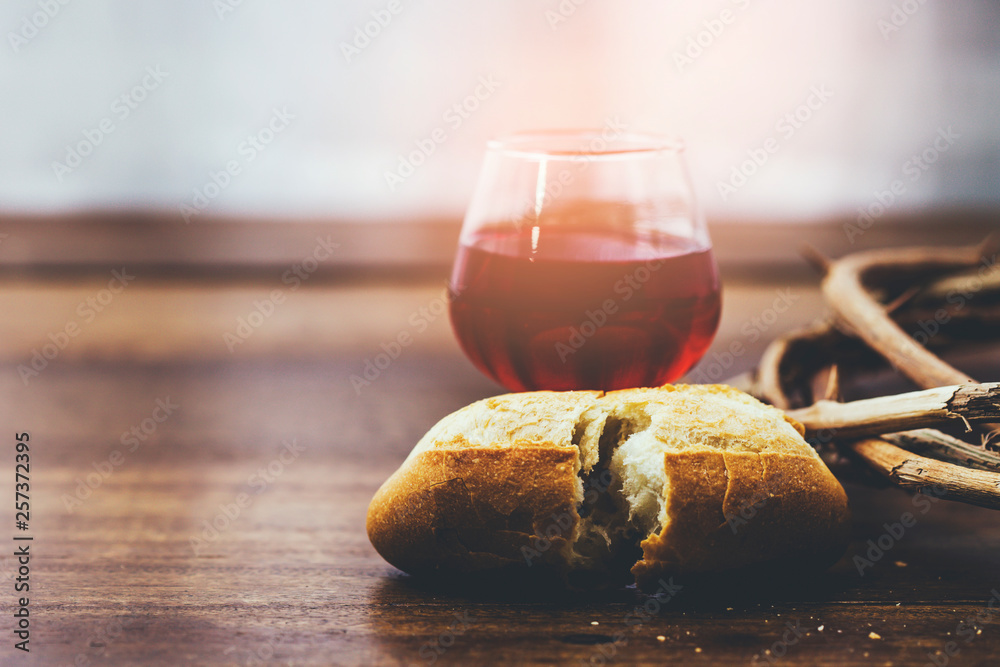 Close up of bread and a cup of Grape juice with crown of thorn on ...