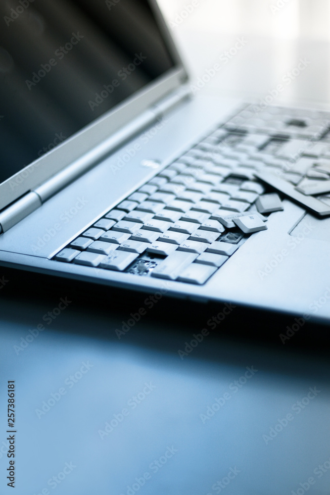 Silver laptop with broken keyboard. A close-up picture of part of ...