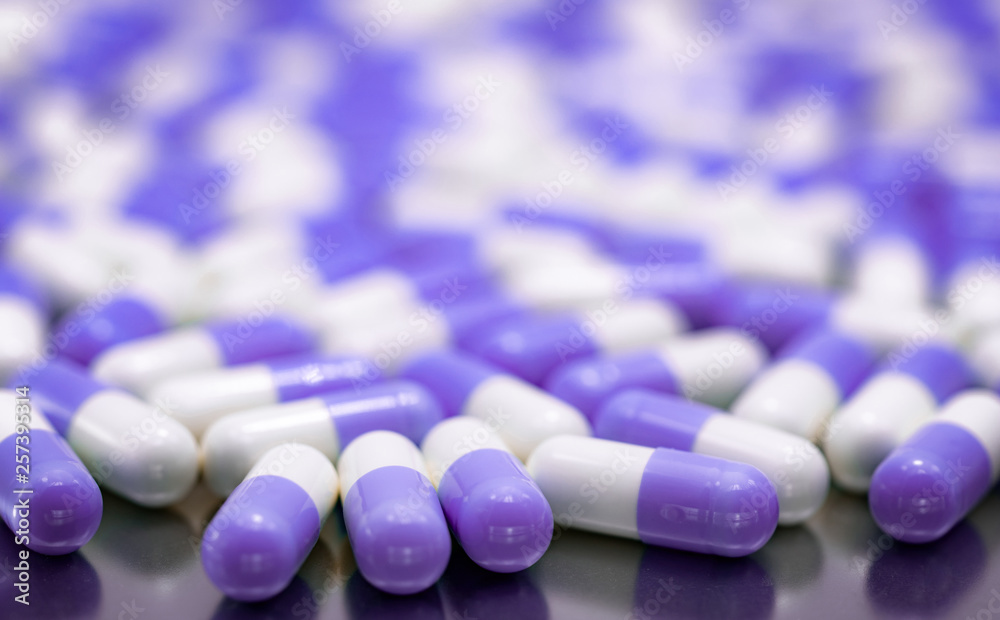 Selective focus purple and white capsule pills on stainless steel drug ...