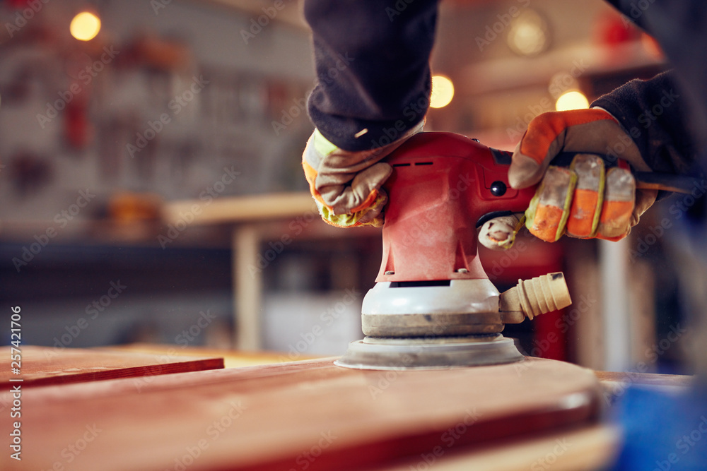 Male carpenter using orbital electric sander in a retro vintage ...