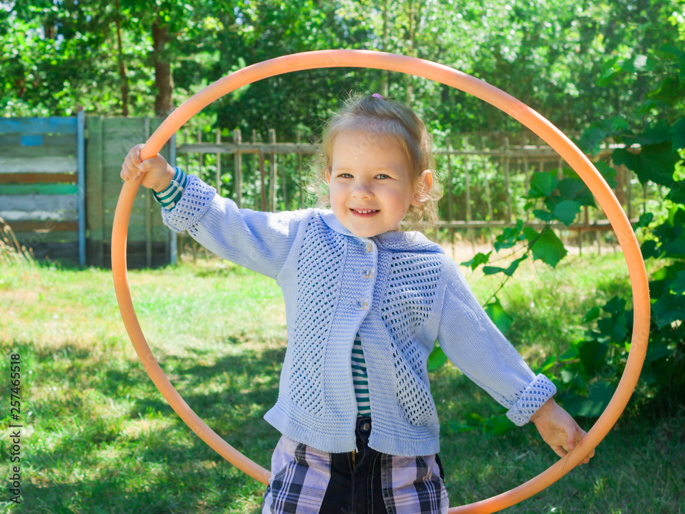 Little baby girl learns to deal with hulahup. The child holds the hoop ...