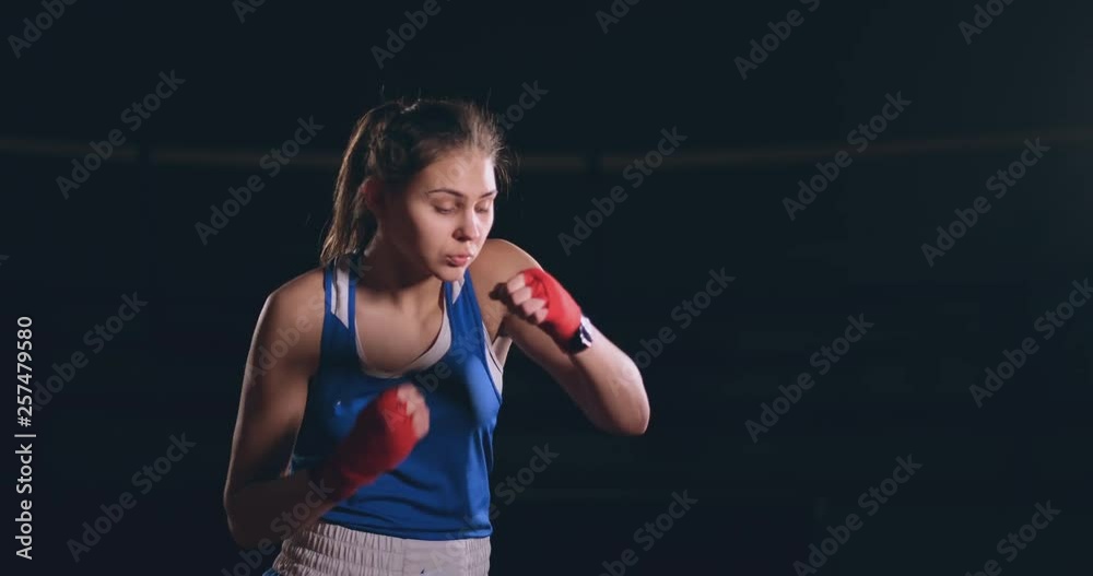 A beautiful woman conducts a shadow fight while practicing hard for ...