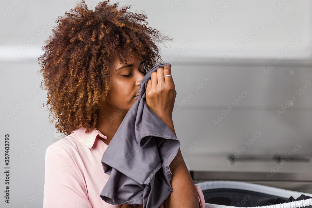 Young black African American woman washing her clothes in a automatic ...