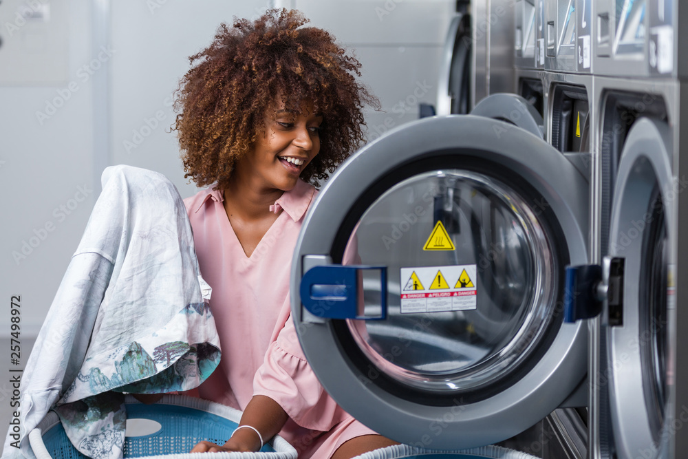 Young black African American woman washing her clothes in a automatic ...