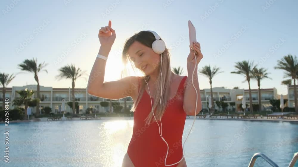 Portrait of beautiful woman in red swimsuit and headphones, dancing and ...