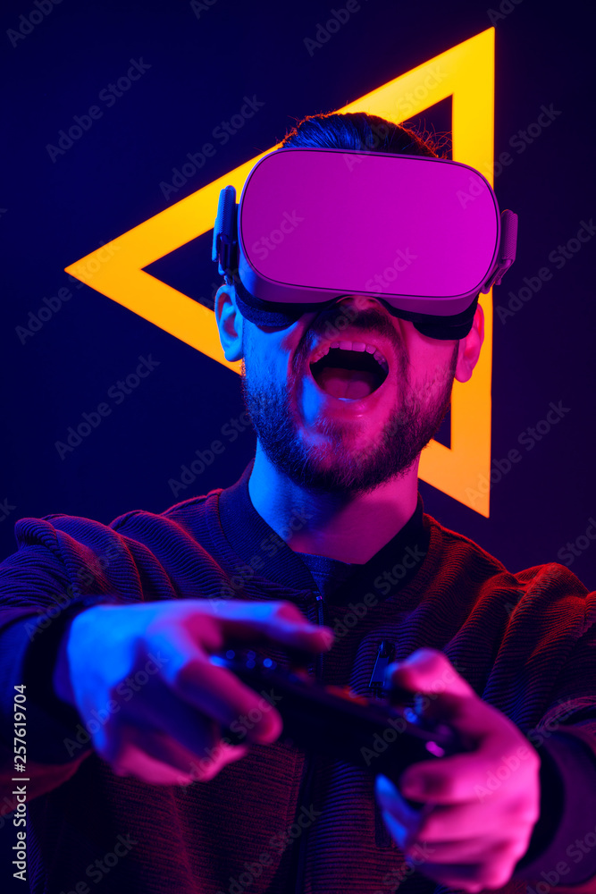 Man wearing virtual reality goggles playing video game with gamepad joy ...