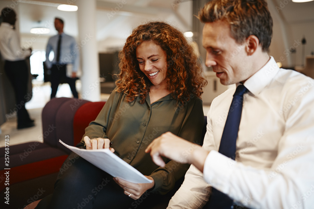 Smiling work colleagues discussing paperwork together on an offi Stock ...
