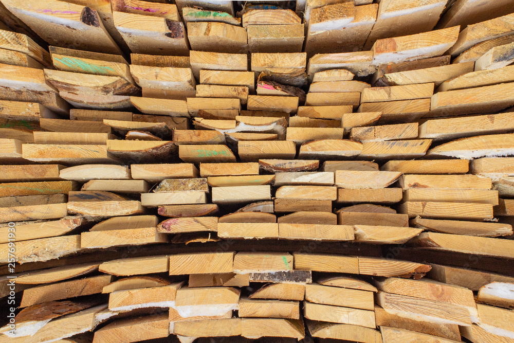 Folded wooden brown and gray planks in a sawmill. Piled alder boards as ...