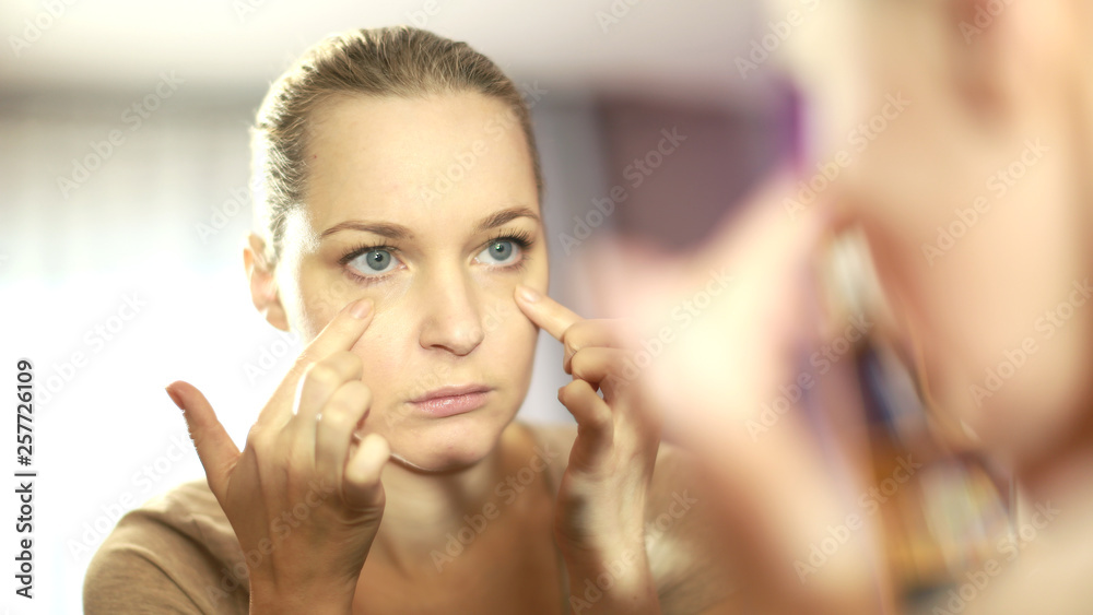 the girl looks in the mirror, dissatisfied with the appearance, pulls ...