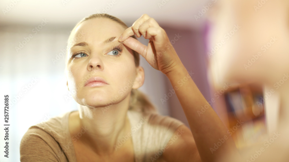 the girl looks in the mirror, dissatisfied with the appearance, pulls ...