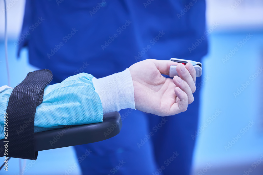 pulse oximeter on finger of patient during surgery. male patient lying ...