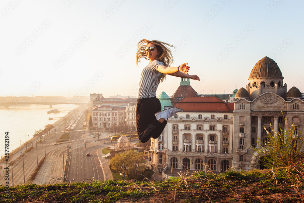 Poster Beautiful woman jumping opposite famous facade and entrance to ...