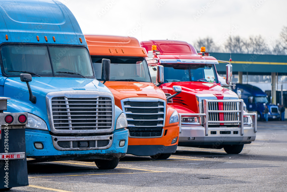Row of different big rigs semi trucks on truck stop parking lot waiting ...
