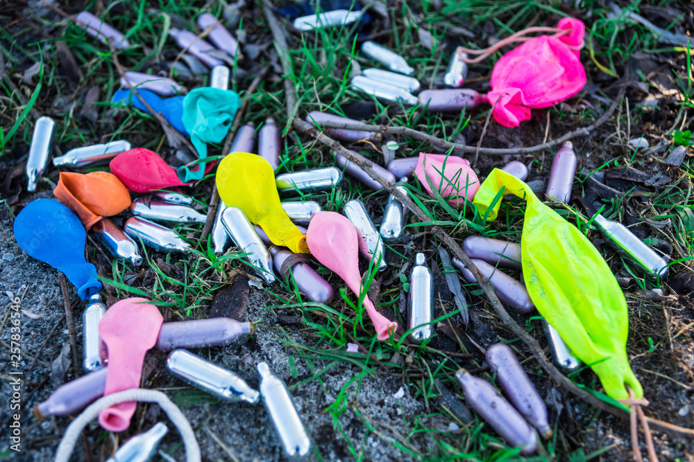 metal bulb and balloons for laughing gas, party drugs, on grass field ...