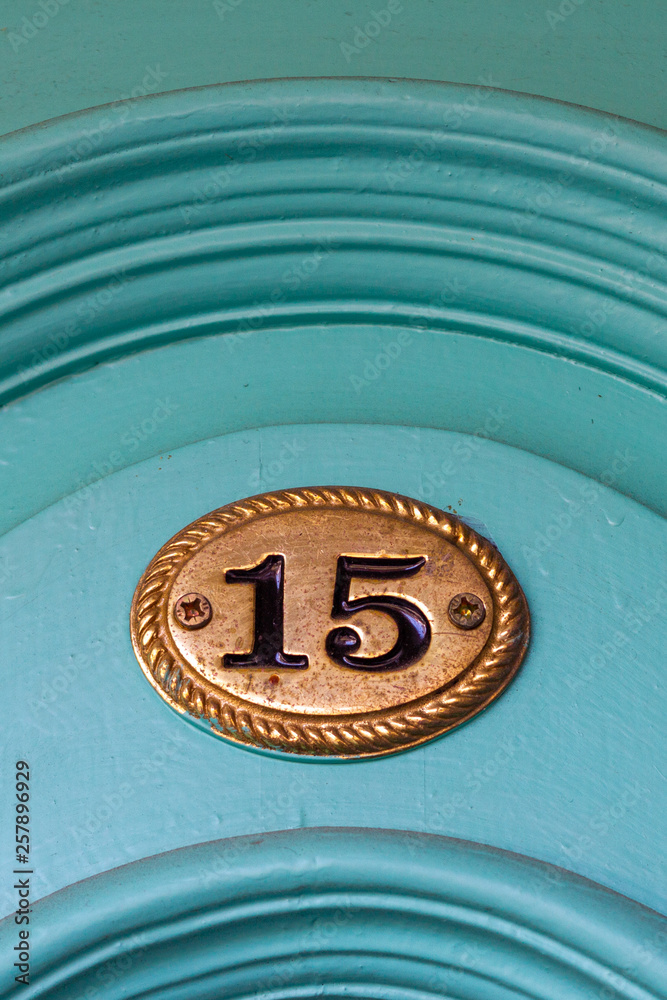 House number 15 with the fifteen in black on a bronze plaque screwed to ...