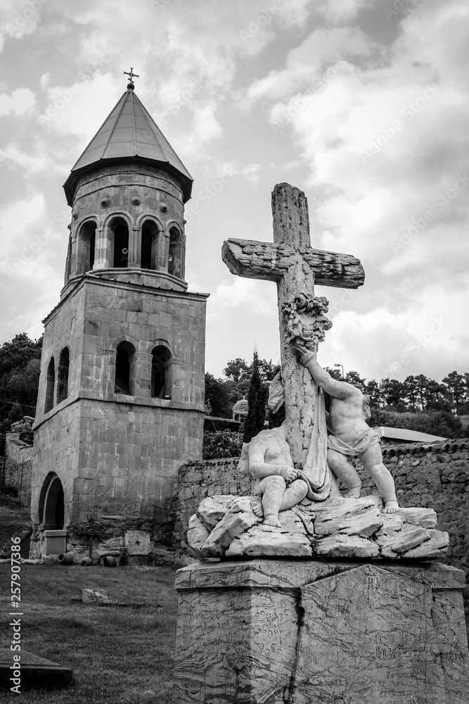Church tower and tombstone with a cross and two headless angels ...