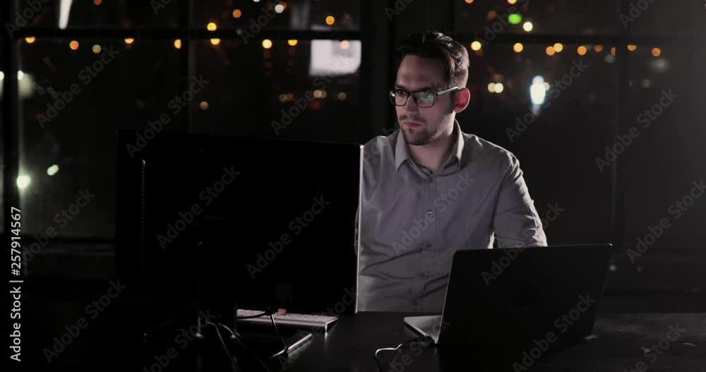 Young programmer man in glasses is working in the office overtime at ...