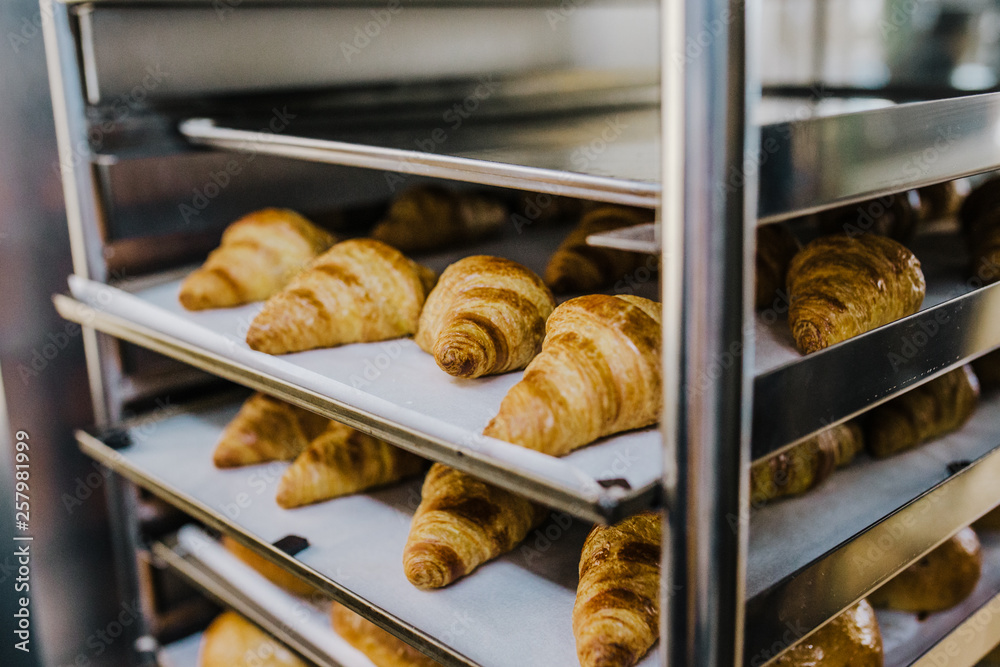 .Working woman using the bakery oven to bake the croissant of the day ...