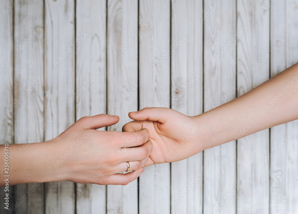 Two hands are joined on a wooden background. Love, friendship, respect ...