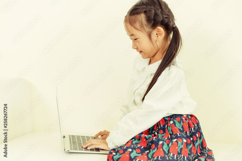 Little happy kid using laptop computer sitting on white sofa. Childhood ...