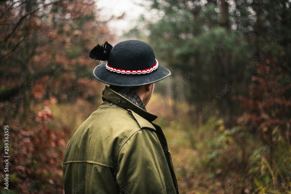 Young forester in traditional and folklore coat and hat with feather ...