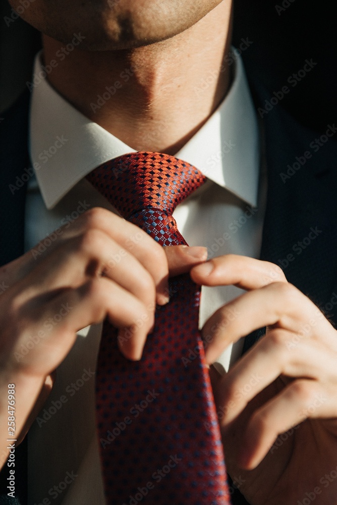 Male model in black suit and red tie poses for men's clothing ...