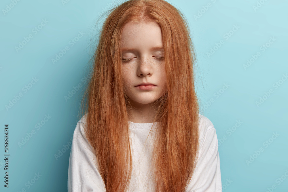 Close up shot of attractive redhead little girl keeps eyes shut, feels ...