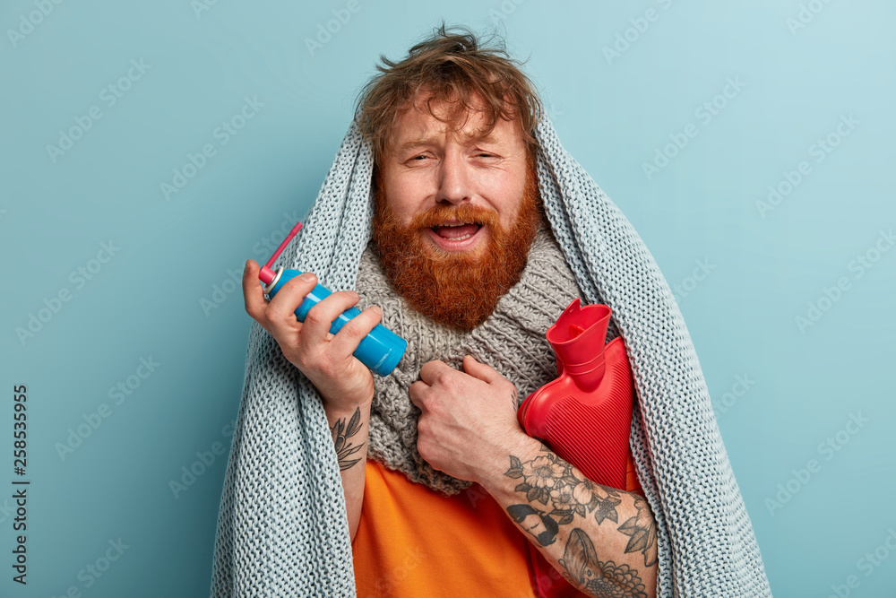 Sad unhappy young man cries in despair, holds aerosol for curing thore ...