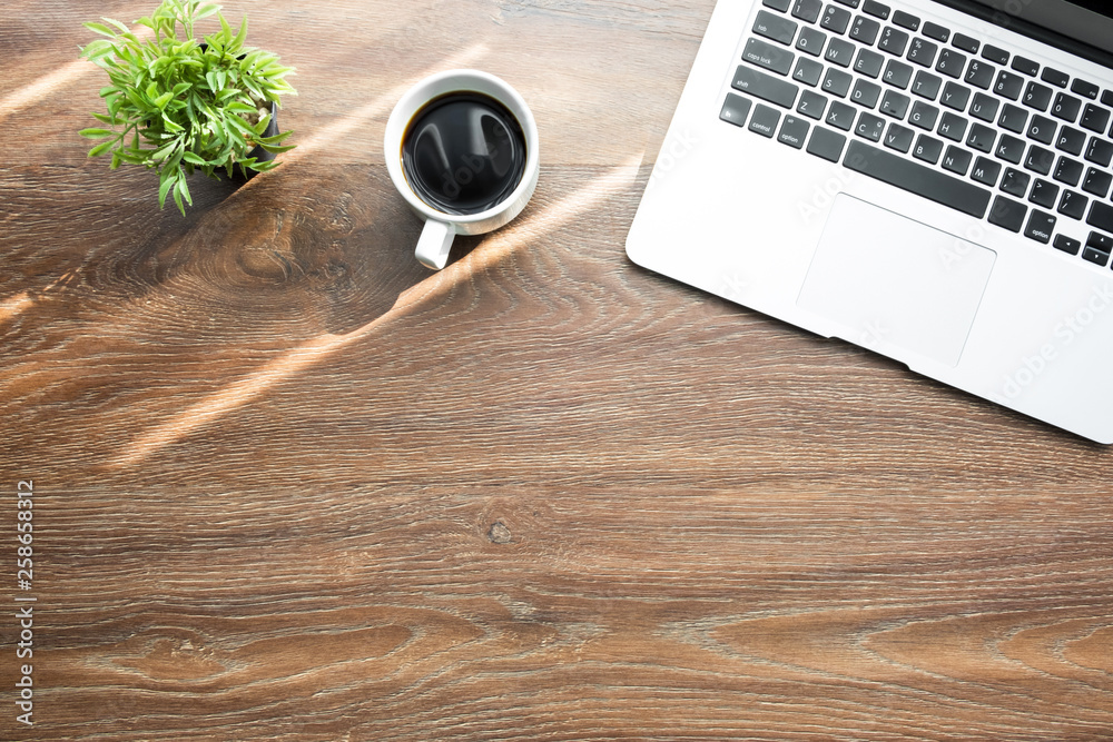 Wood office desk table with laptop, cup of coffee with morning sun ...