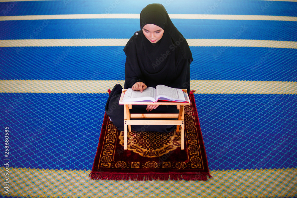 Young muslim woman reciting Al Quran inside a mosque. Al Quran is an ...