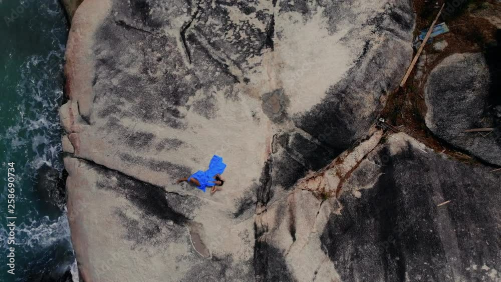 Aerial drone view of beautiful brunette girl in blue long dress dancing ...