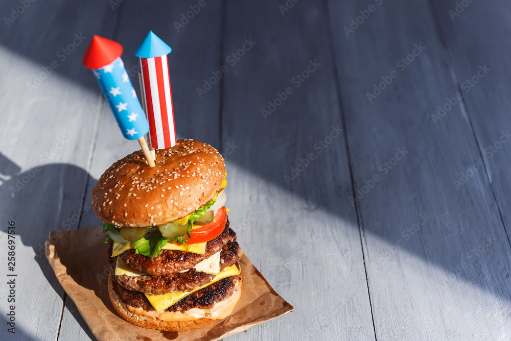 a big burger with three juicy beef patties bonded with American flag ...