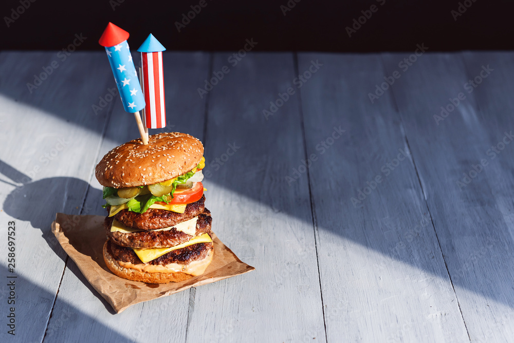 a big burger with three juicy beef patties bonded with American flag ...