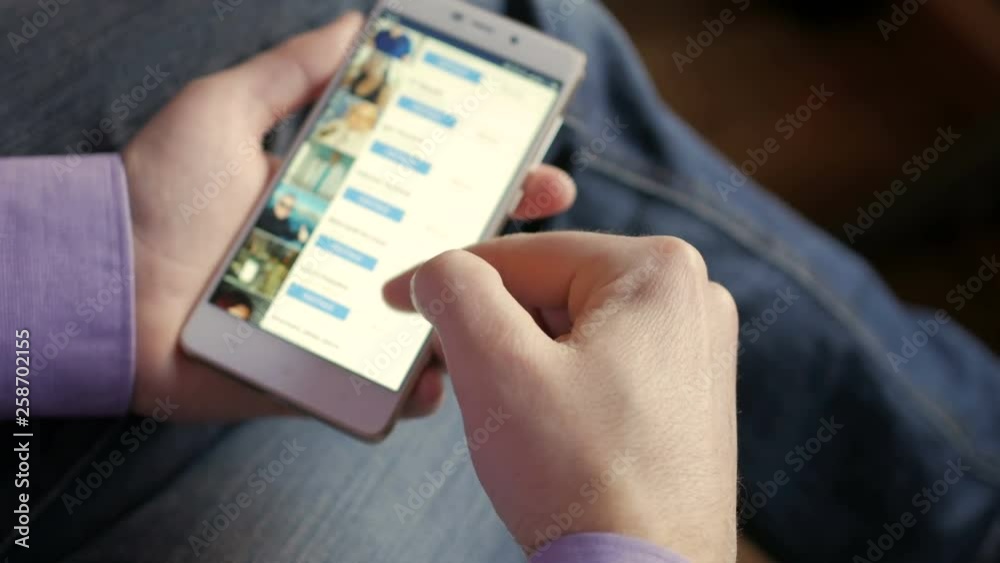 Man using his smartphone with to scroll an account feed, scrolling news, tapping on screen. The ...