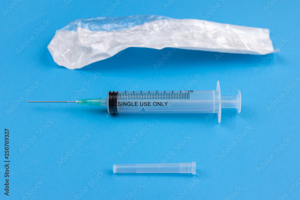 Disposable syringe and its packaging on a blue background top view ...