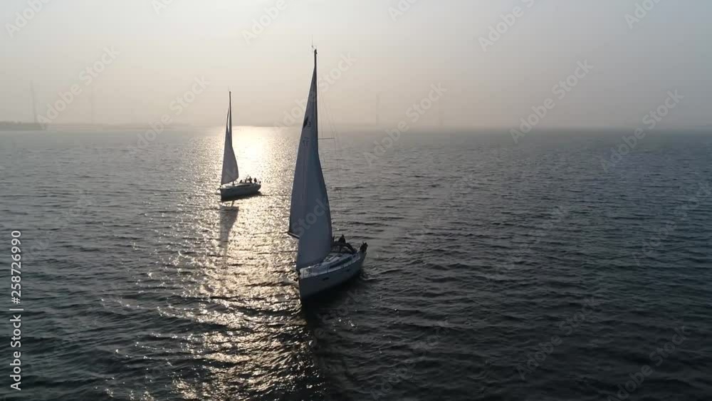 Wideo Stock: Aerial view of two sloops at sundown are sailing boats ...