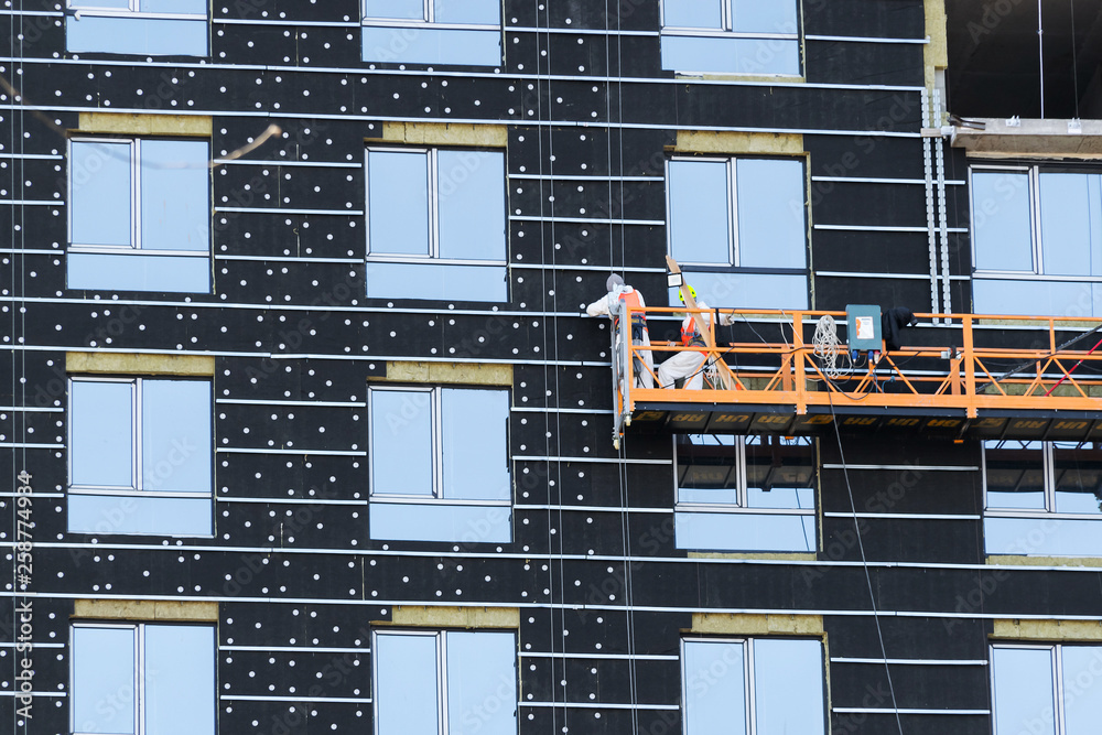 construction winch with workers on a concrete wall of a high-rise ...