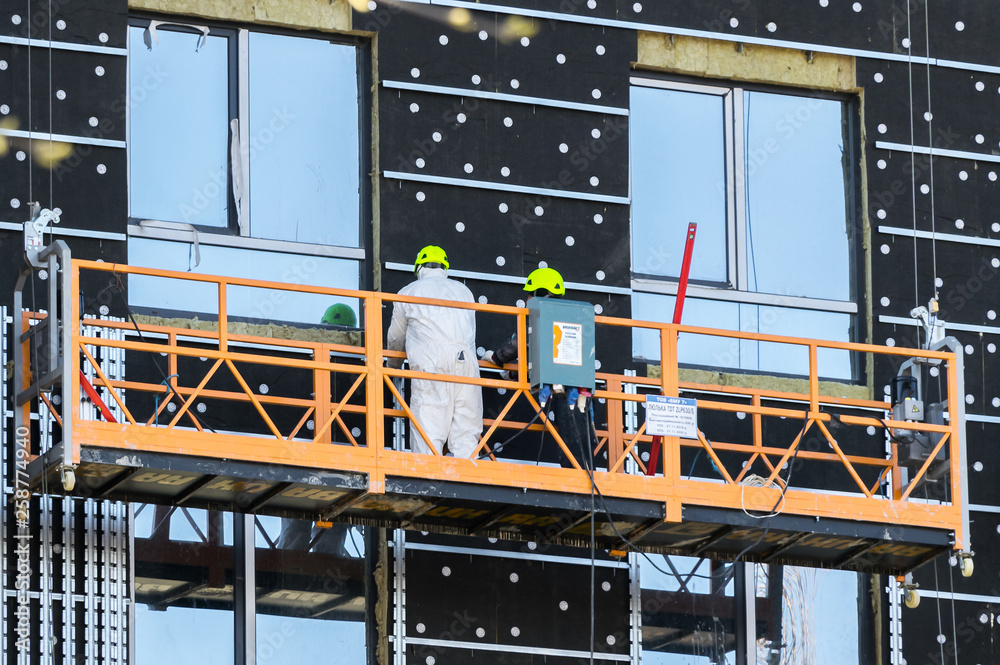 construction winch with workers on a concrete wall of a high-rise ...