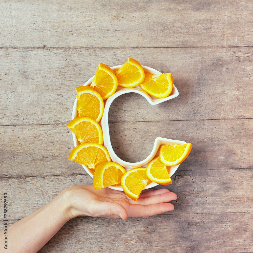 Vitamin C nutrient in food concept. Woman hand holding plate in shape ...