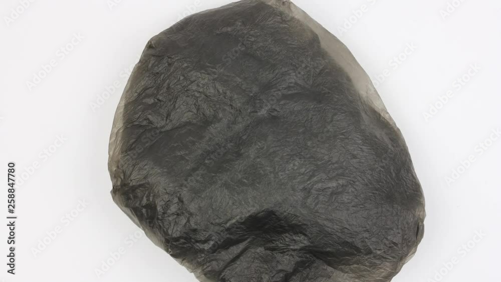 crumpled into a ball used black plastic bag rotates on white background ...