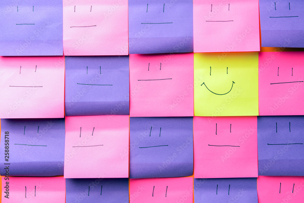 Paper sheet with drawn smiley emoticon among those with serious ones ...