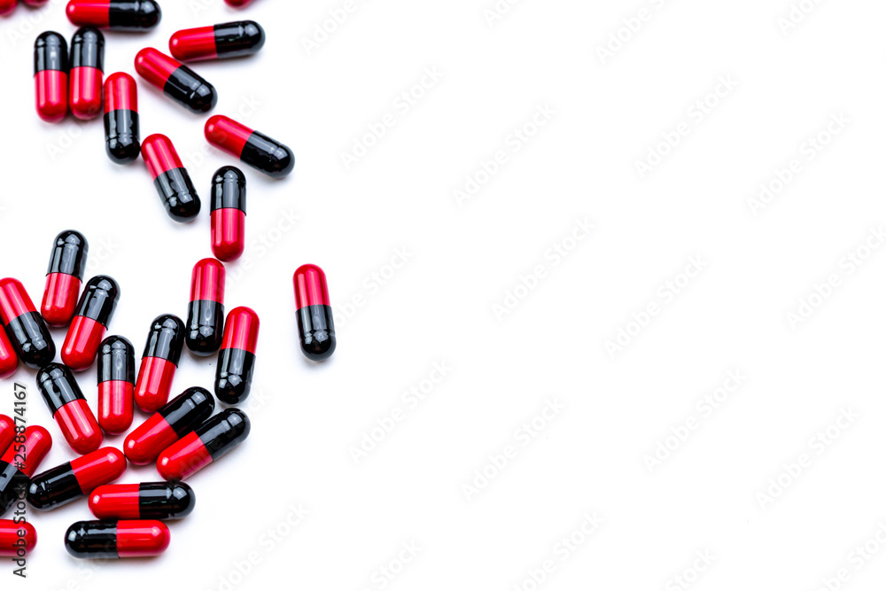 Red-black capsule pills spread on white background. Antibiotic drug use ...