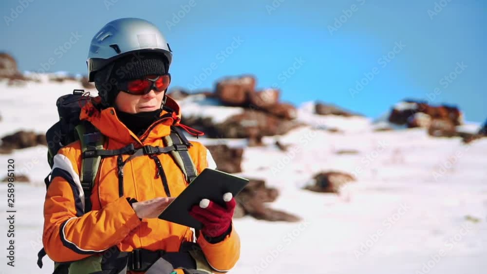 climber in a special outfit stands on a snow-covered slope and checks ...