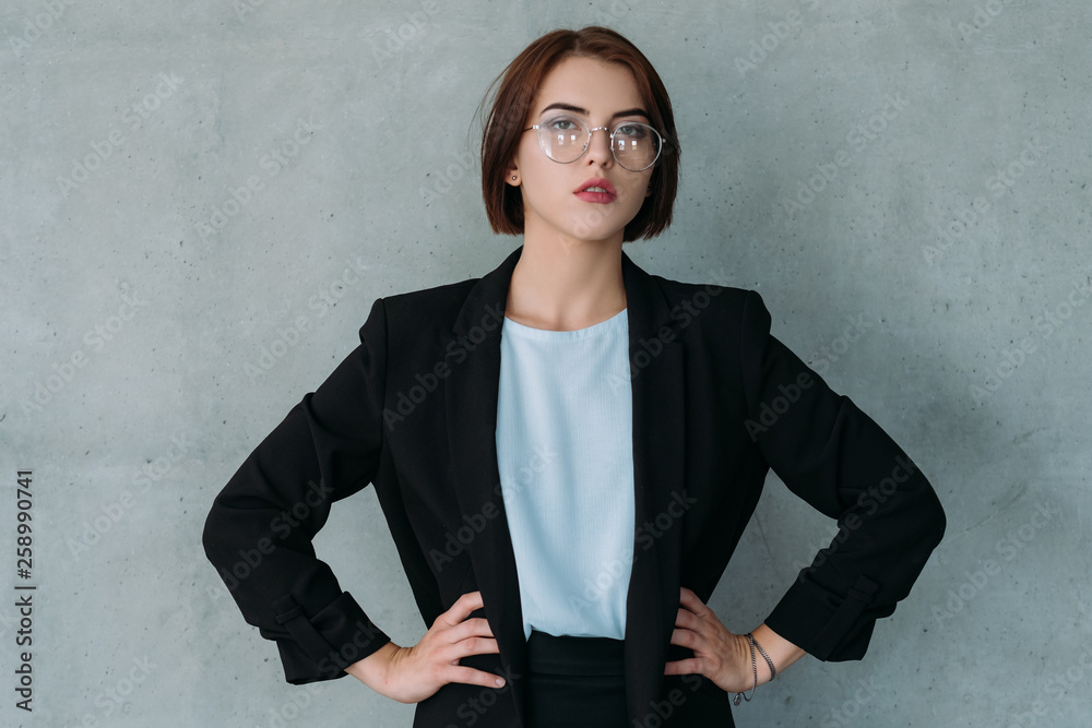 Portrait of young lady boss standing confidently with hands on the hips ...