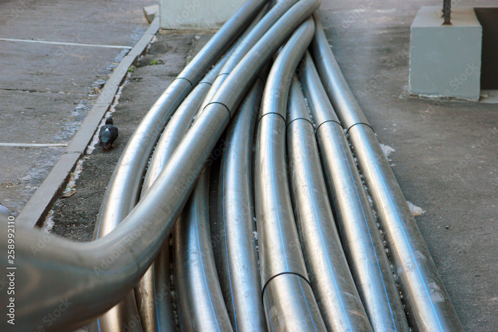 black shiny plastic pipes for electric cables lie in a bundle on the ...