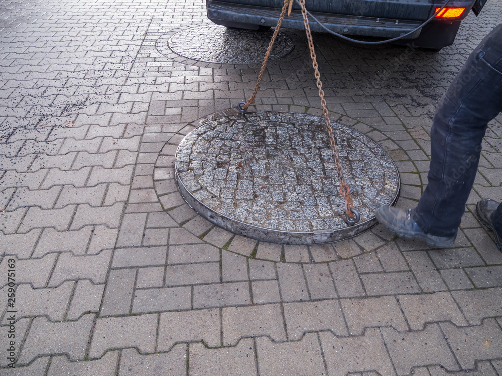 Lifting a heavy manhole cover on a pedestrian zone Stock Photo | Adobe ...