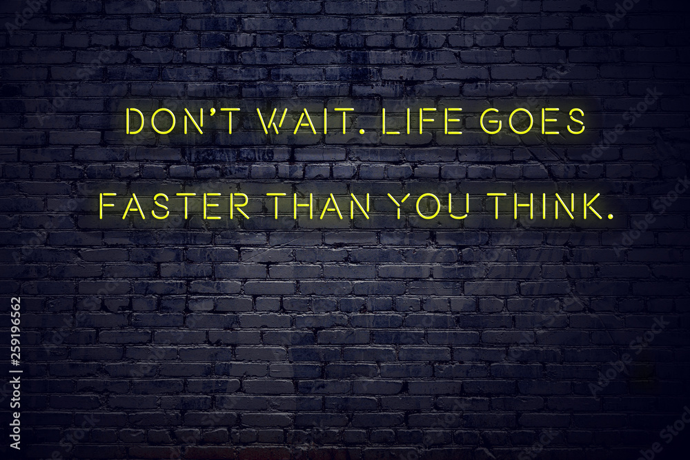 Positive inspiring quote on neon sign against brick wall dont wait life ...