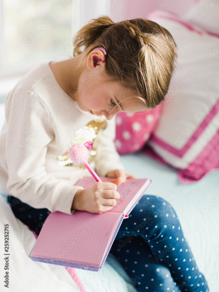 Young girl sitting on bed writing in her diary Stock Photo | Adobe Stock