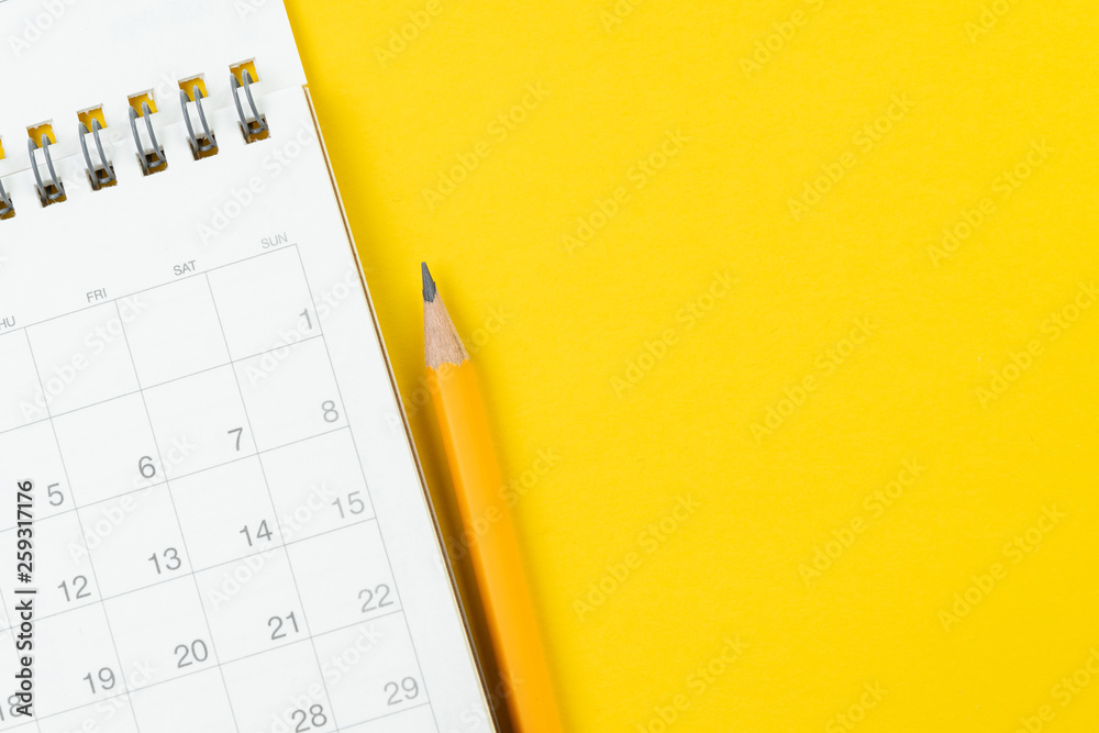 White clean calendar with yellow pencil on solid yellow background with ...