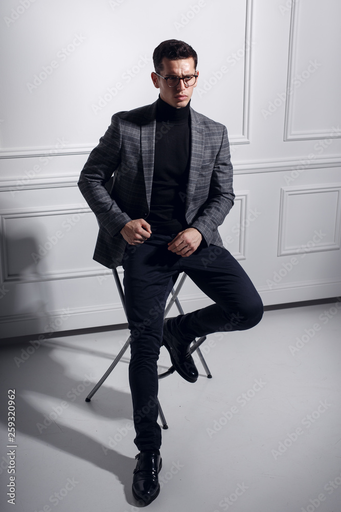 Strong,stylish man in elegantly costume ,black eyeglasses sit on black ...